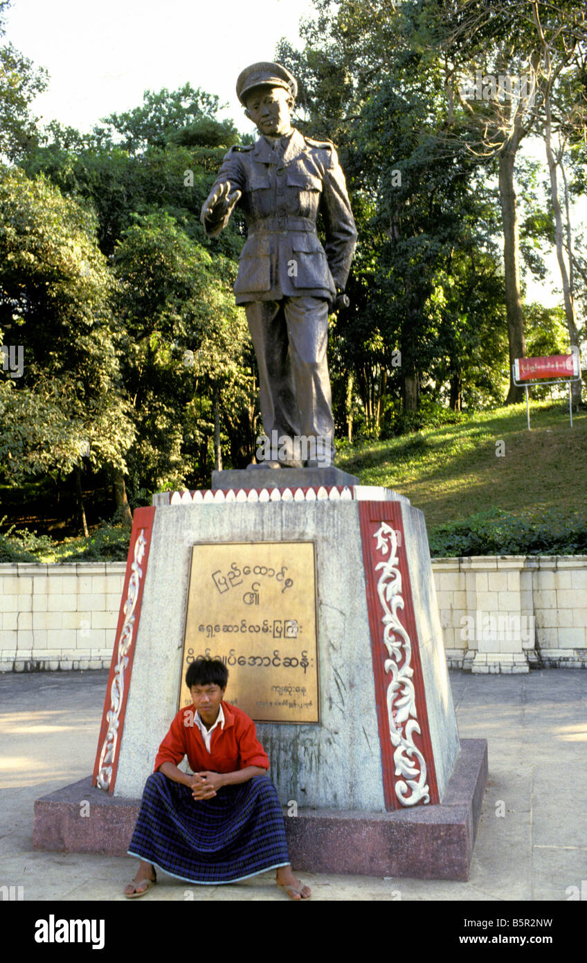 A young man sits at the base of a statue of General Aung San, modern ...