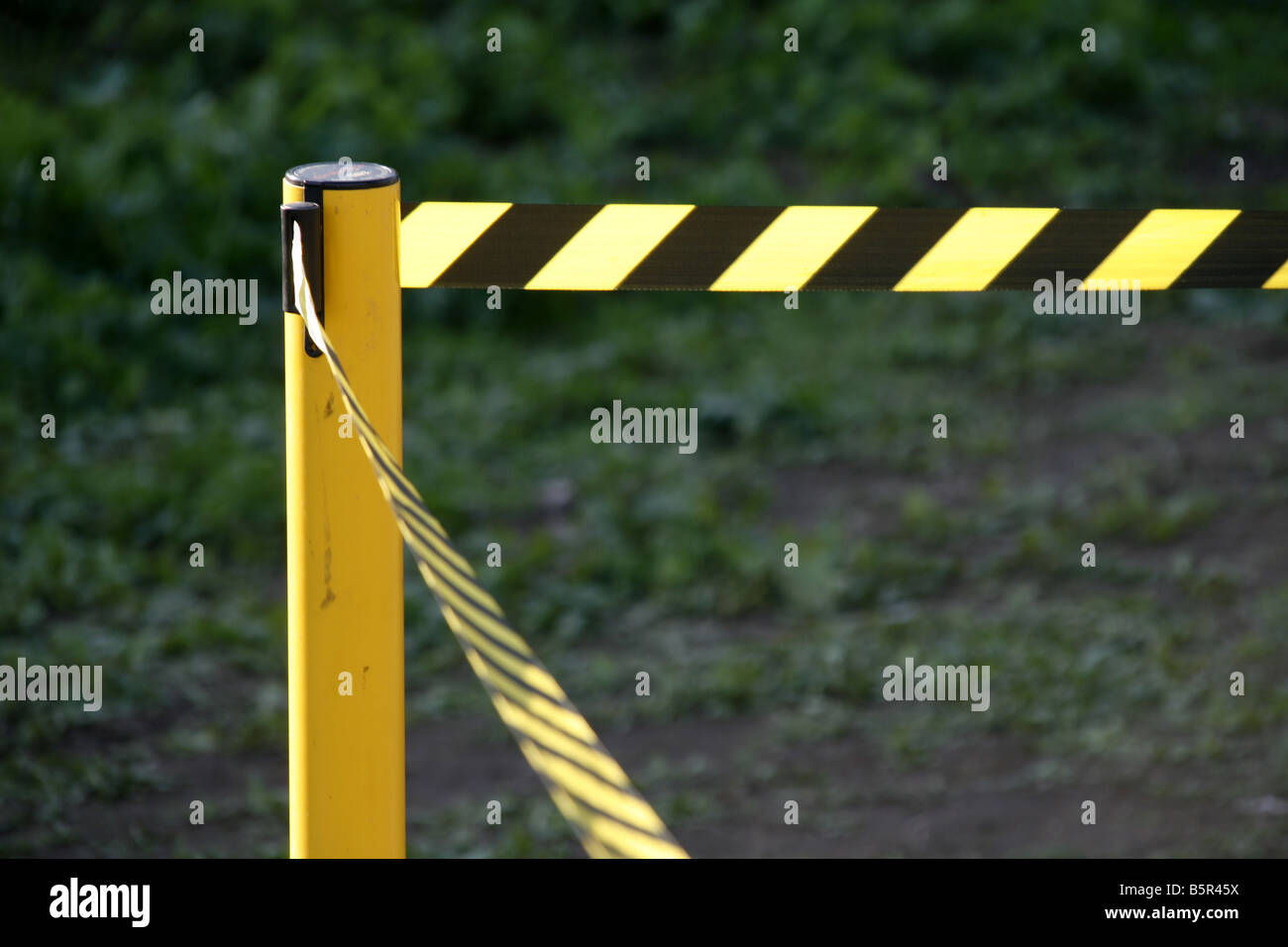 yellow black public temporary tape barrier in field Stock Photo - Alamy