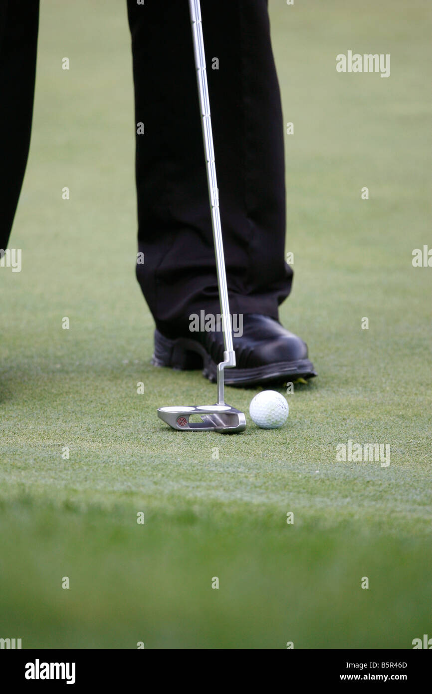 Close-up of a golfer's leg with a putter and ball on the putting green ...