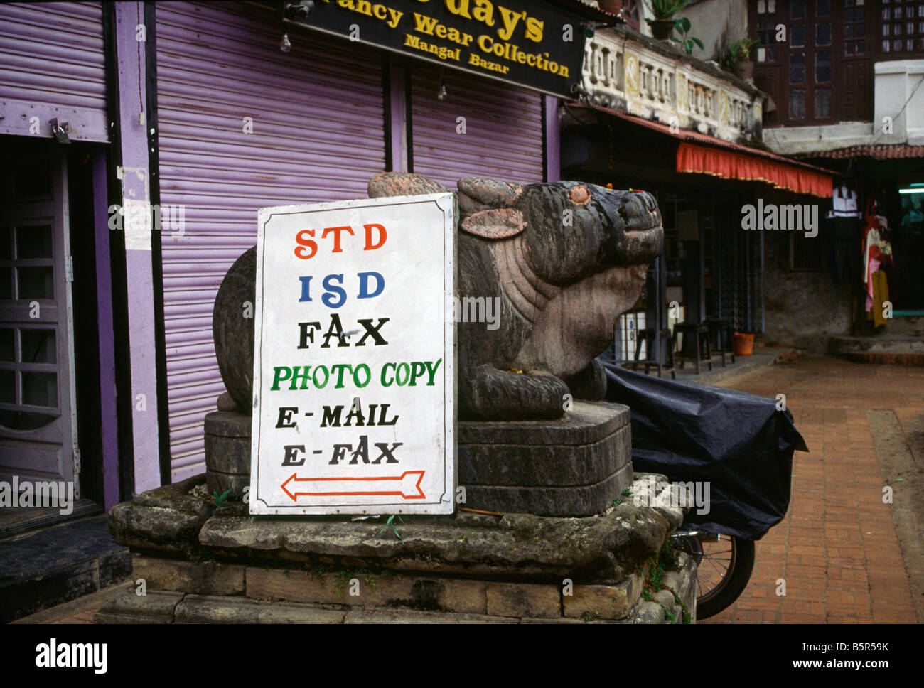 A modern communications sign rests on an ancient statue of the Hindu ...