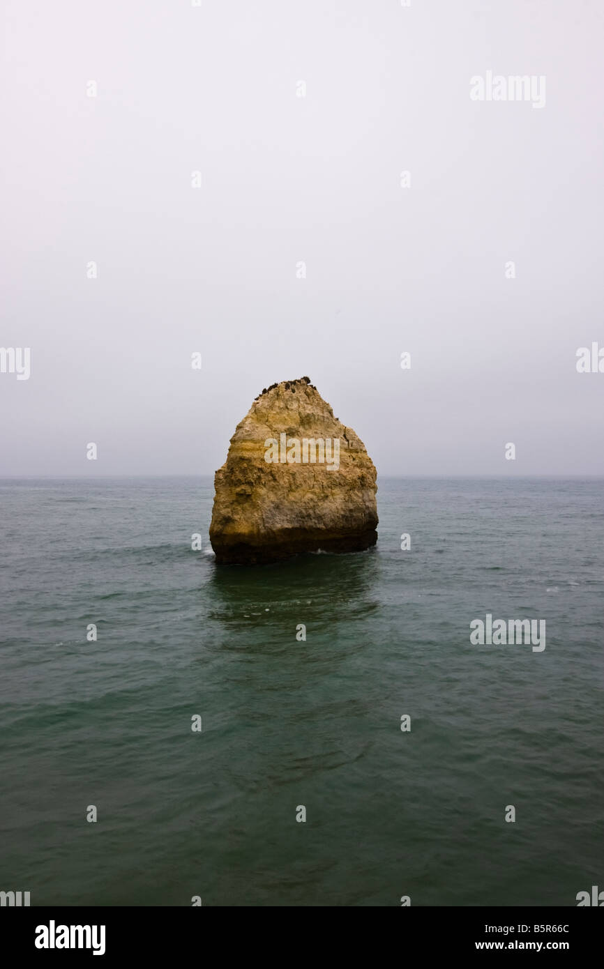 Big rock in the middle of the ocean barely seen due the myst Stock ...