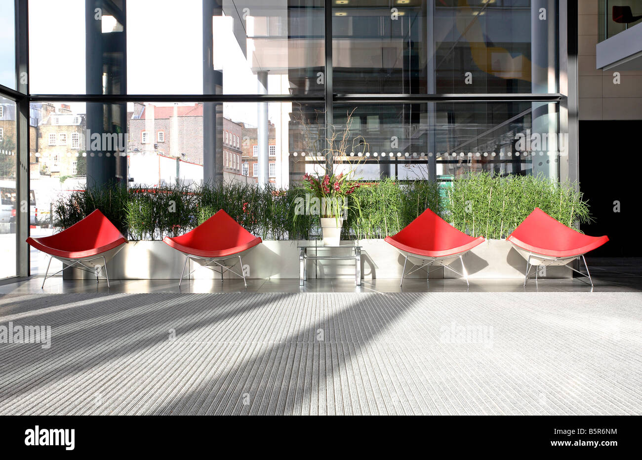 group of 4 red triangular designer chairs in office block with sun ...
