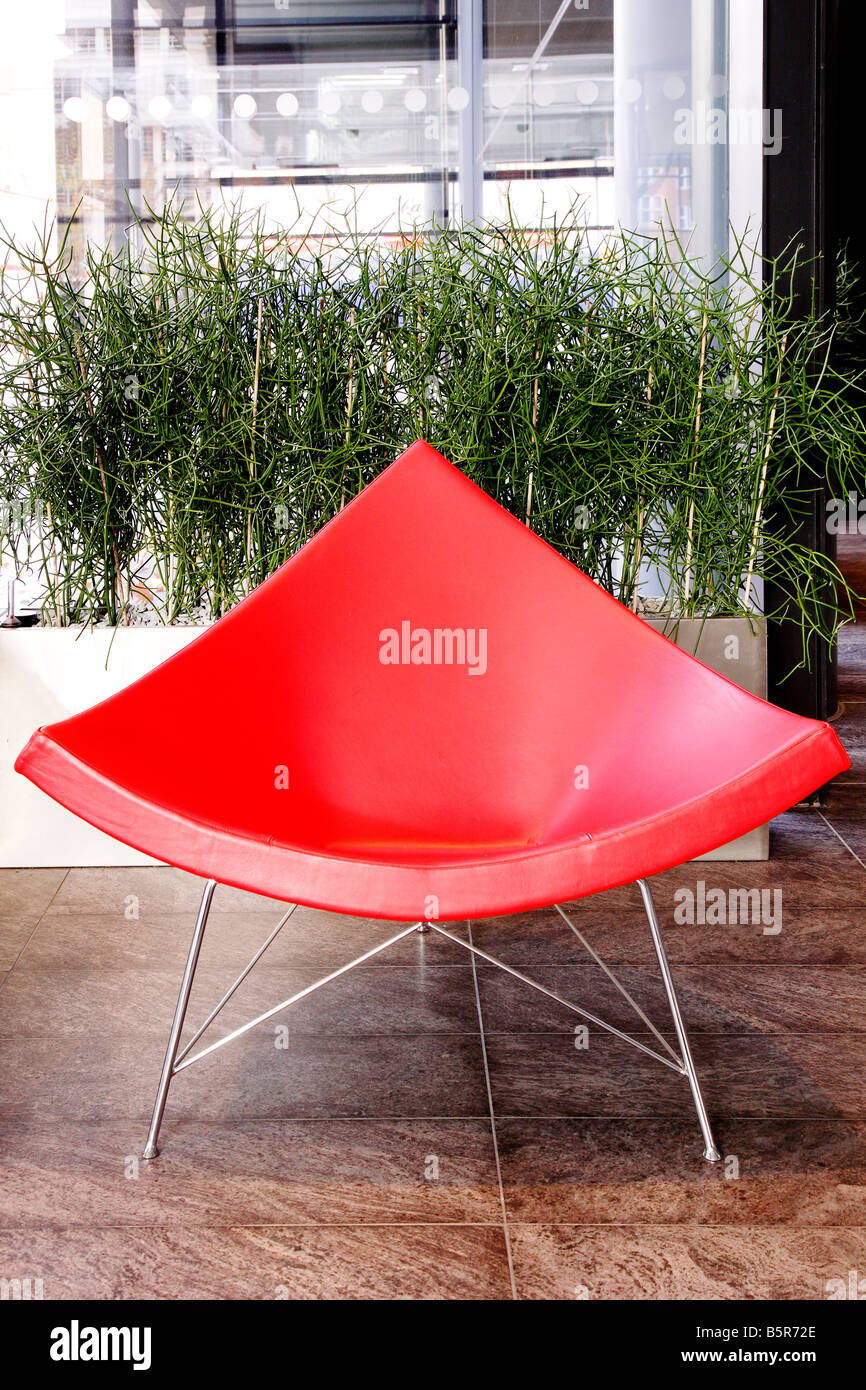 designer triangular red three legged empty chair in office interior ...