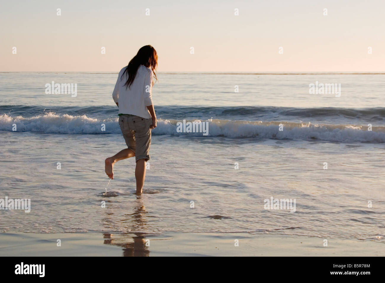 A young woman wading in the surf at the beach Carmel by the Sea ...
