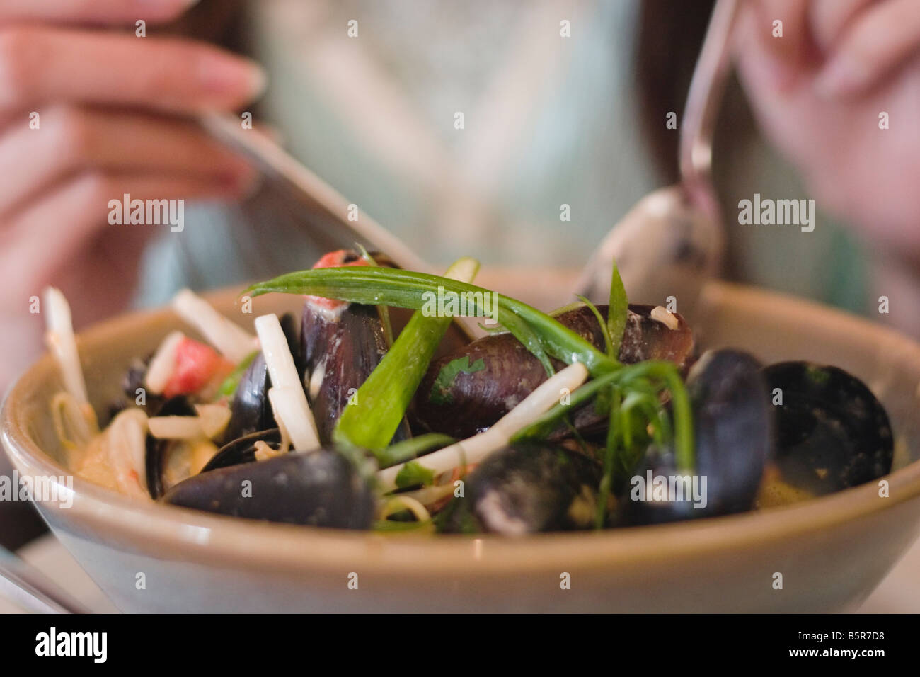Young woman eating a bowl of seafood chowder at a restaurant Stock ...