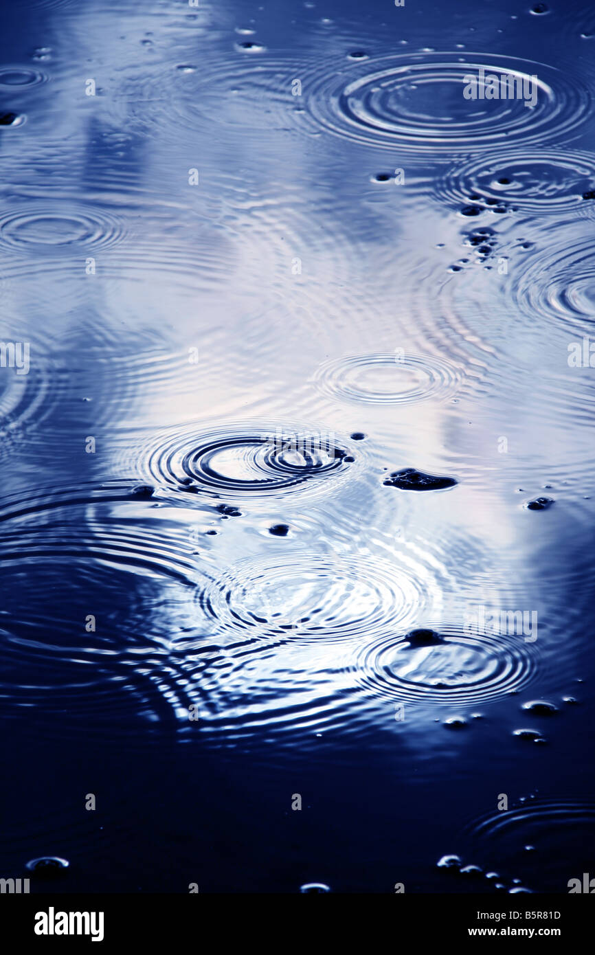 rain drops falling in cold blue water puddle in street at night Stock ...