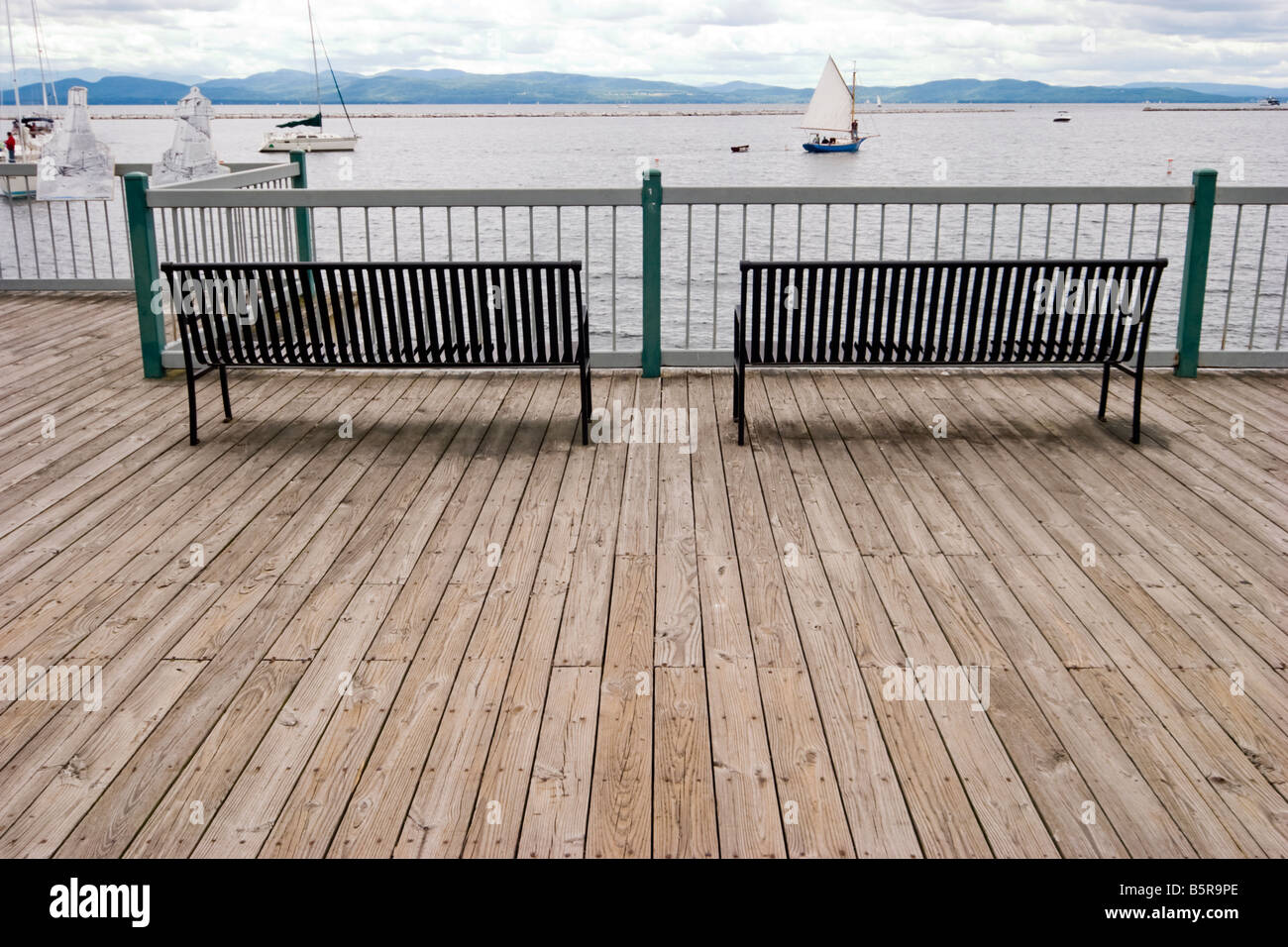 Empty metal benches on a boardwalk in front of a large lake Stock Photo ...