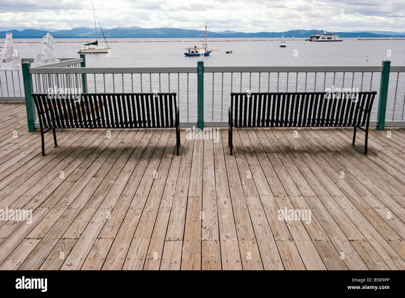 Empty metal benches on a boardwalk in front of a large lake Stock Photo ...