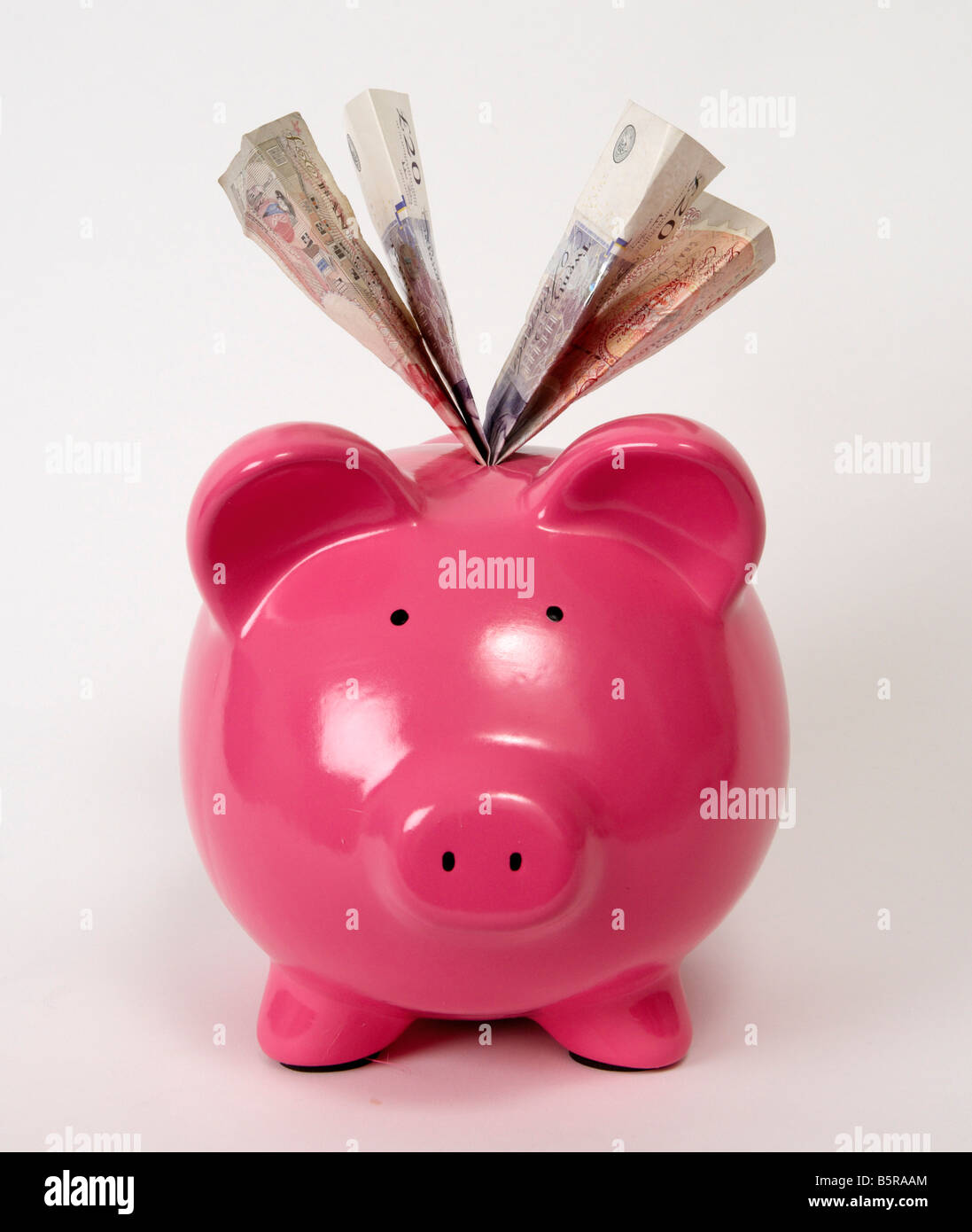 A pink piggy bank filled with pound sterling bank notes Stock Photo - Alamy