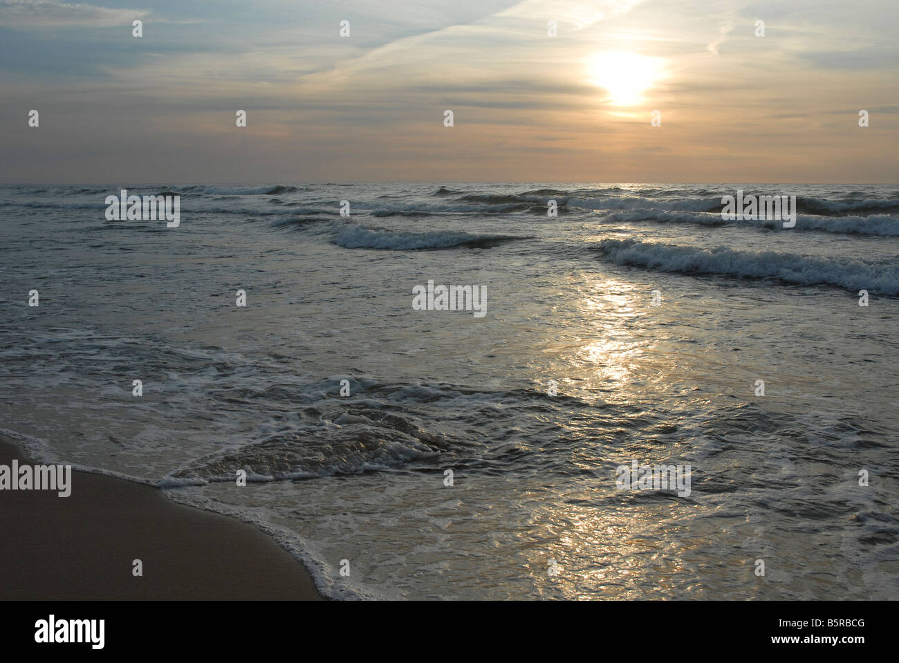 Waves on beach in sunset Stock Photo - Alamy