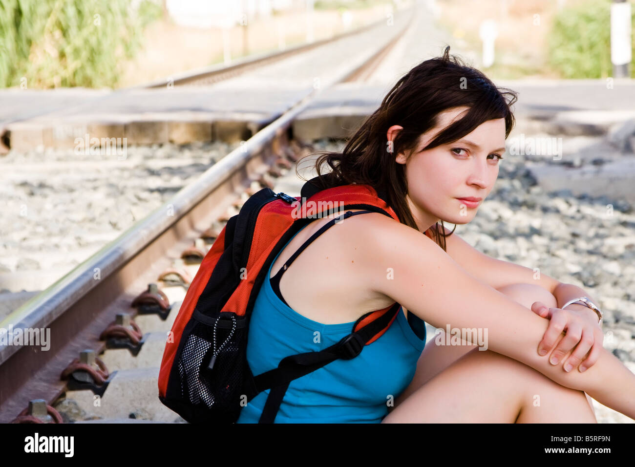 Young backpacker woman sitting near railway Stock Photo - Alamy