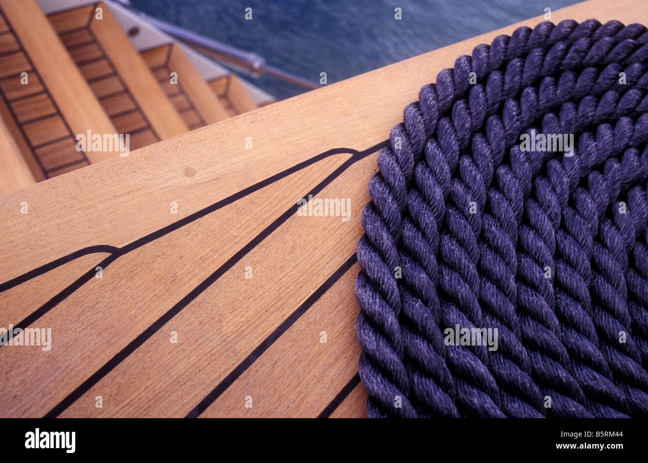 Coiled black rope on a wooden boat deck Stock Photo - Alamy