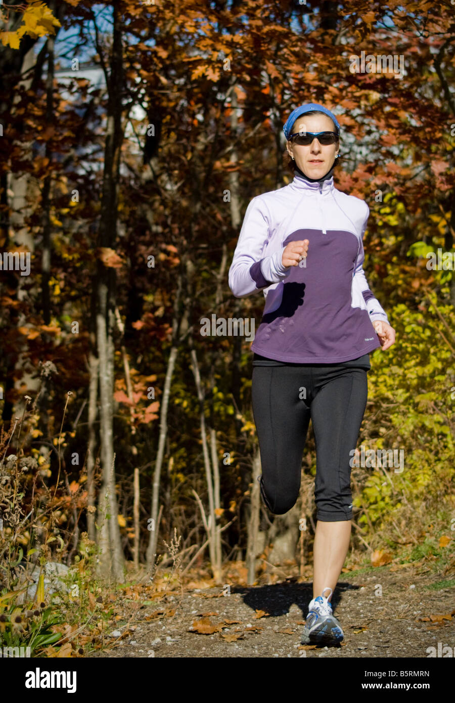 Woman trail runner emerging from the woods Stock Photo - Alamy