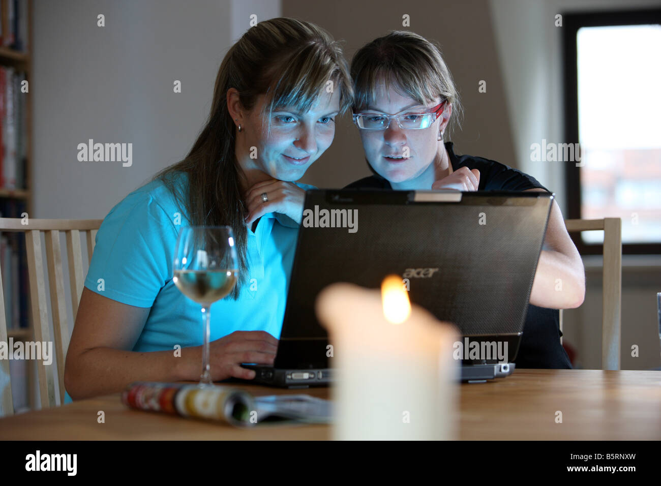 2 Young women in an apartment working on a laptop computer surfing the ...