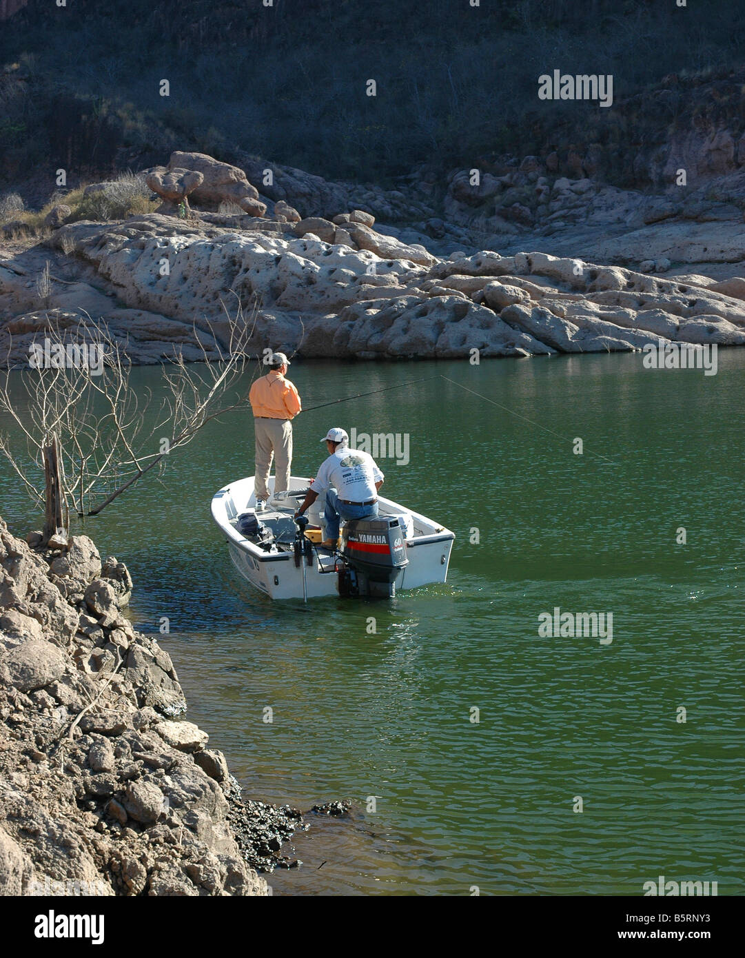 A bass angler fishes for largemouth along a scenic rock bluff on Lake ...