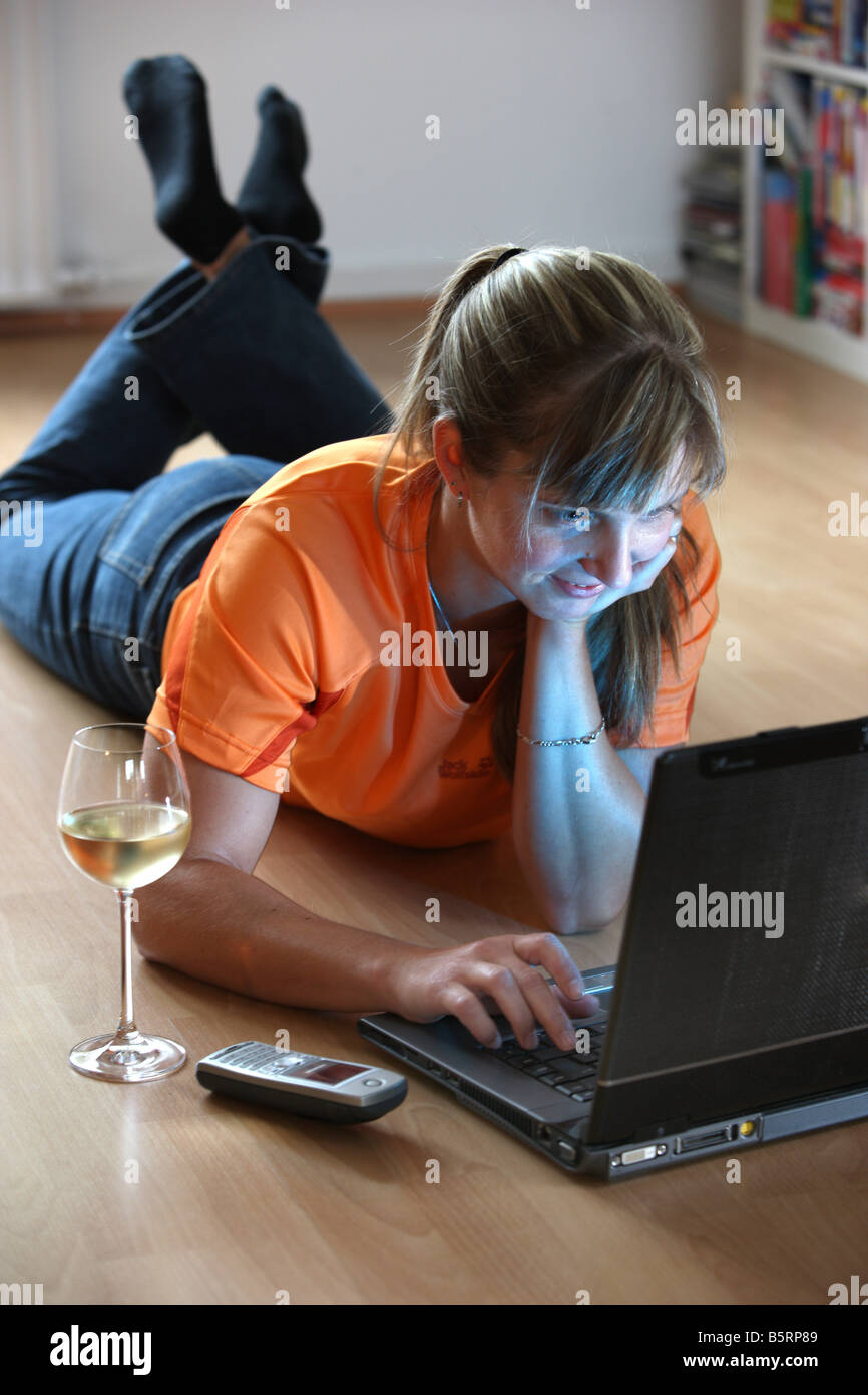 Young woman in her apartment working on a laptop computer surfing the ...