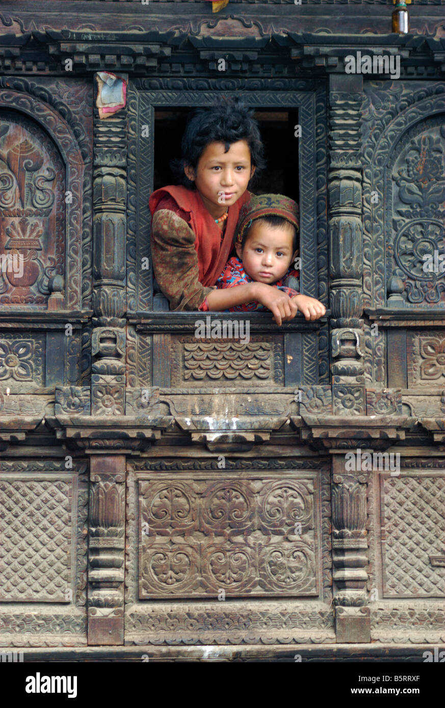 Two Tamang girls watch from a window in their elaborately carved wooden ...