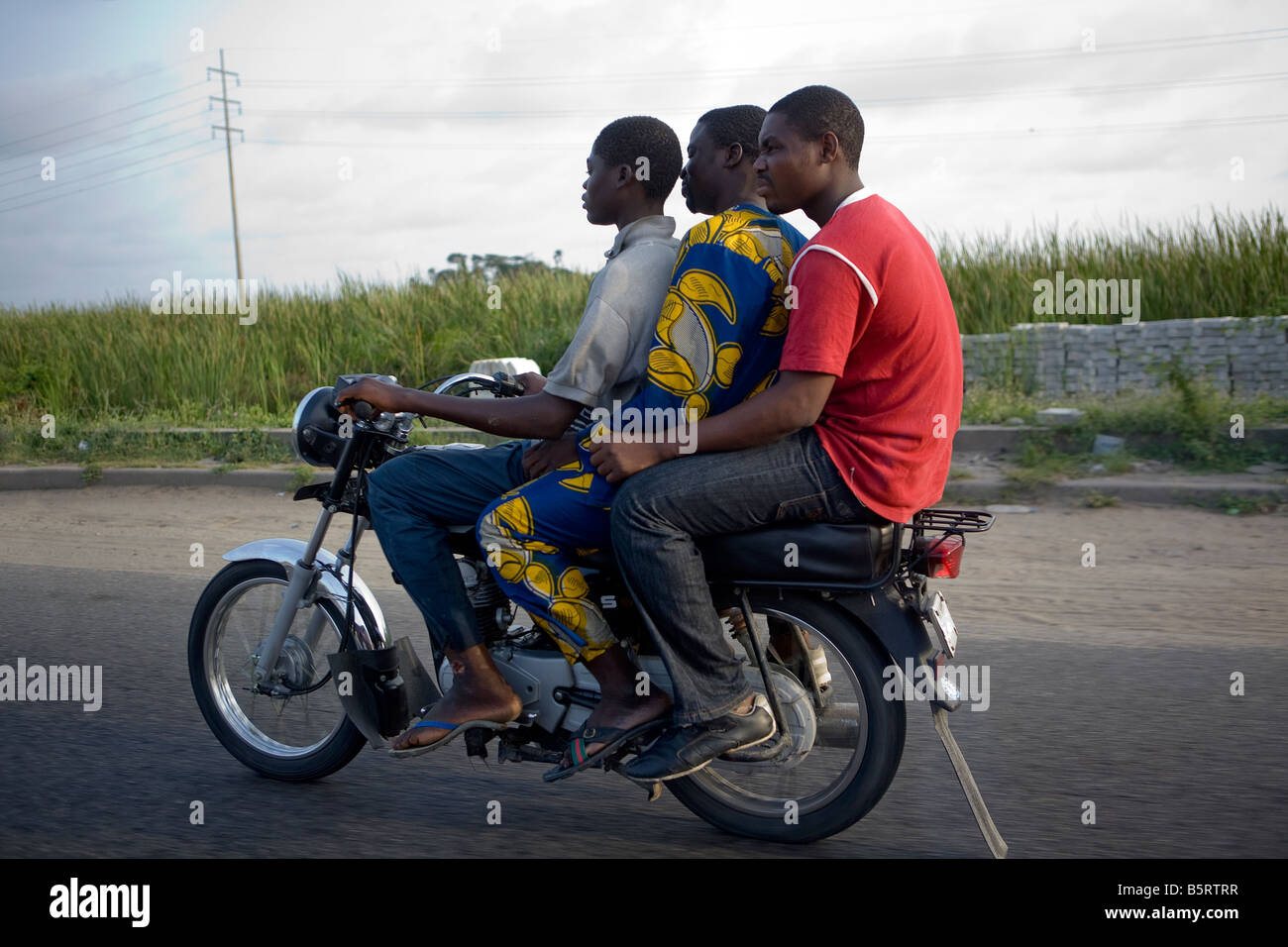 Three men share a motorbike along the road leading out of Lagos ...
