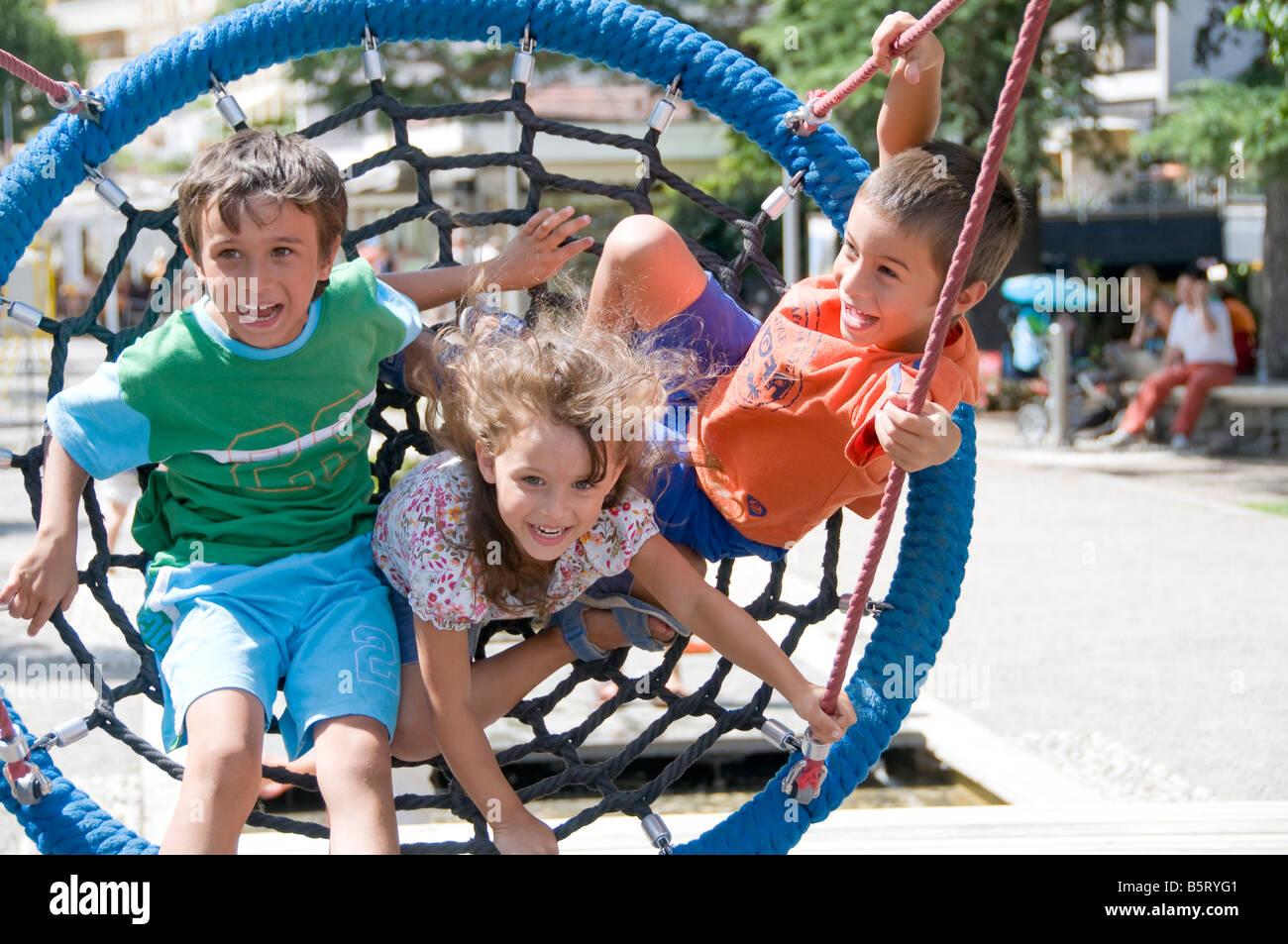 Children playing on a large playground net swing Stock Photo - Alamy