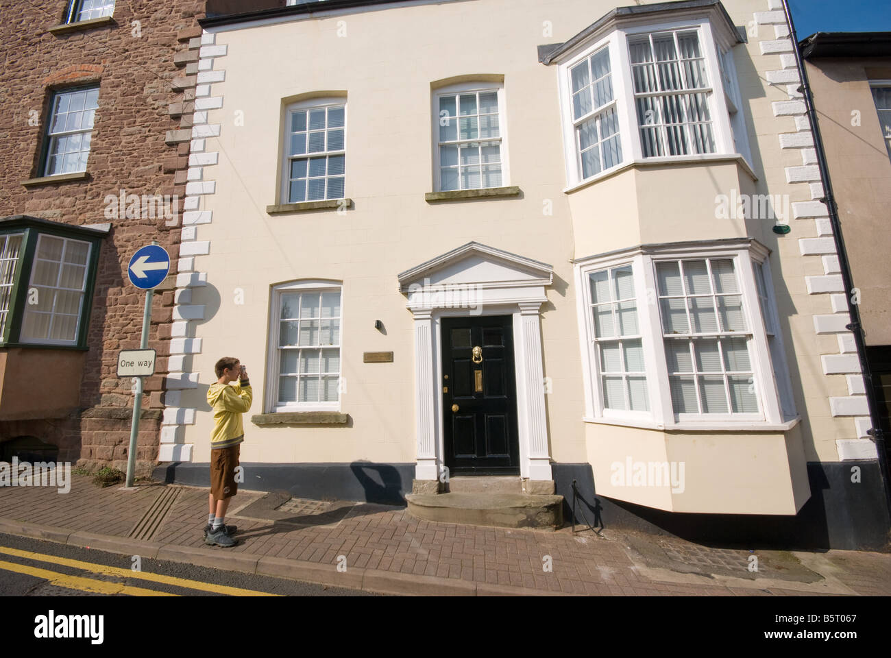 Boy photographing the front of a traditional period Georgian house ...