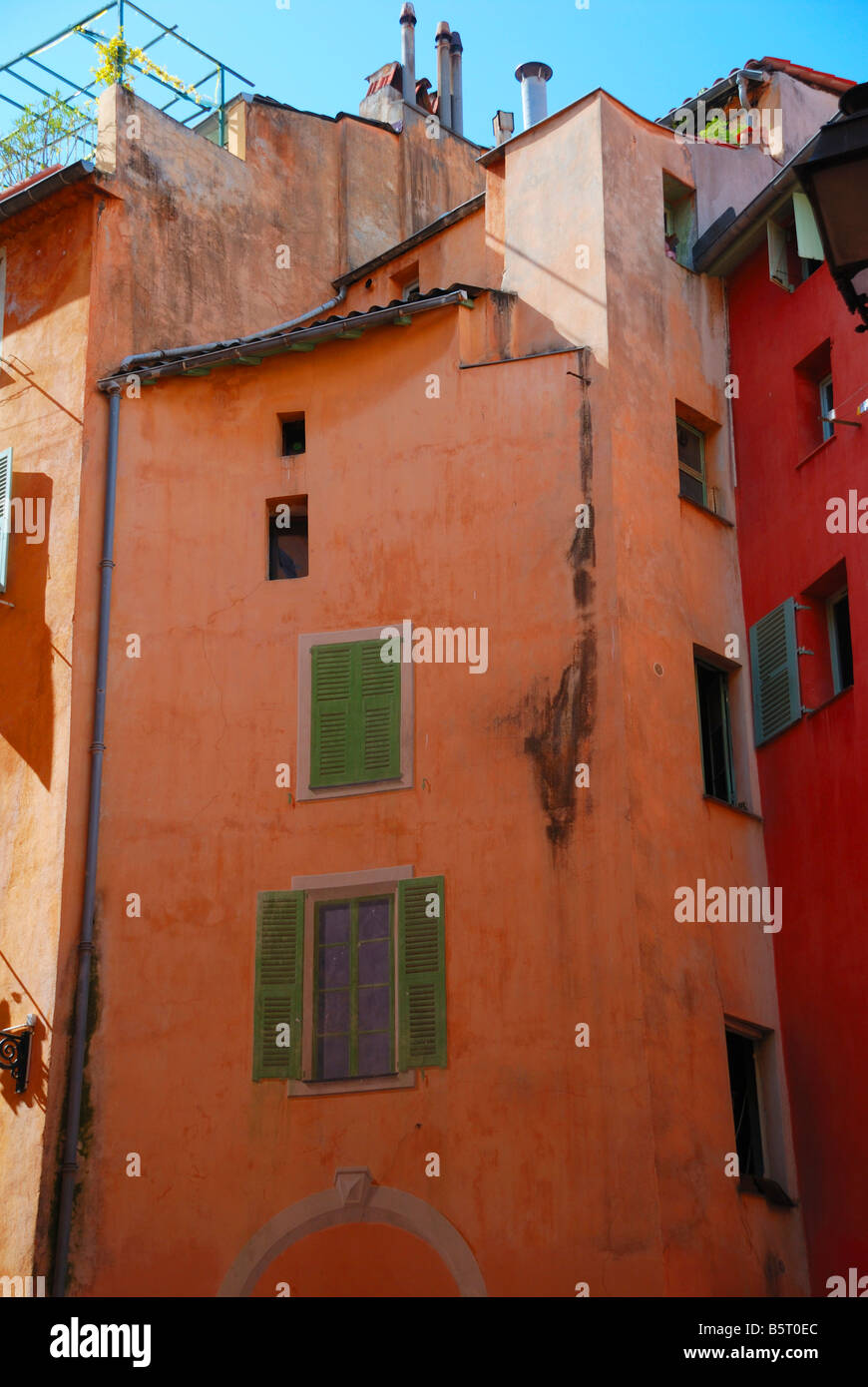 Different windows with green shutters on reddish wall, dense building ...