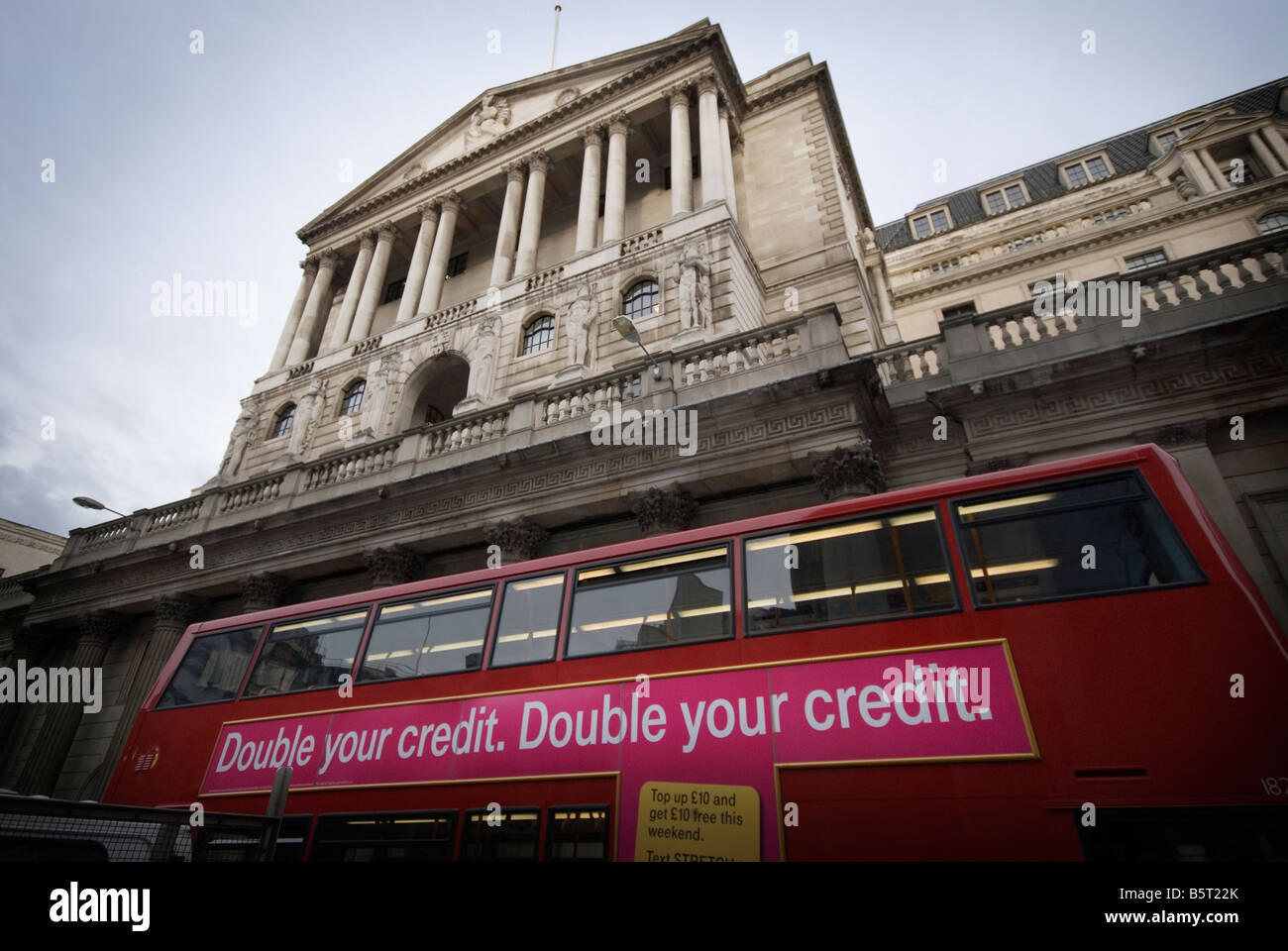 Red double decker bus driving past the Bank of England in the City of ...