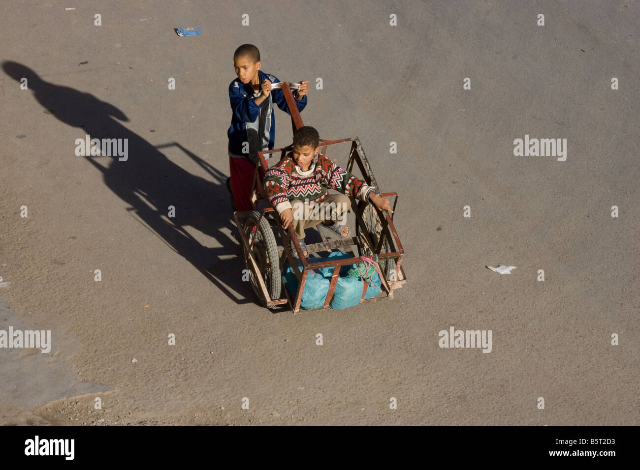 Boy pushing his friend in a cart, Er Rachidia, Morocco, North Africa ...