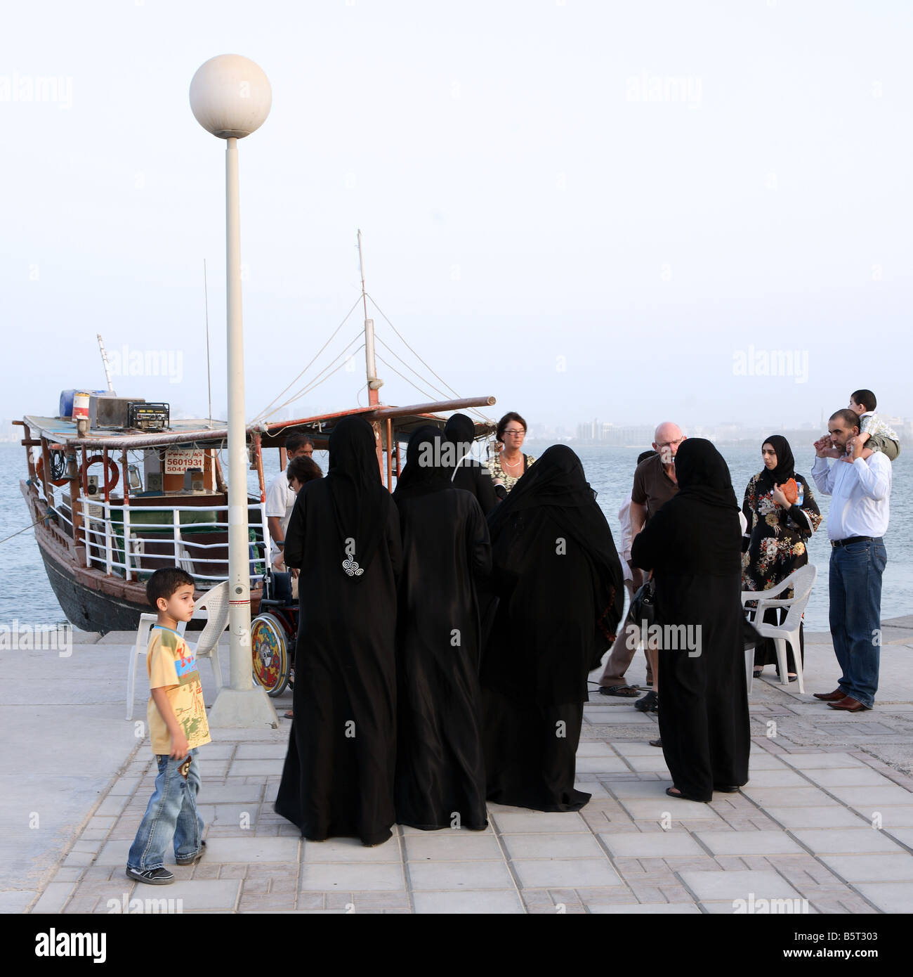 Qatari women in black abayas and foreigners at dhows that give trips ...
