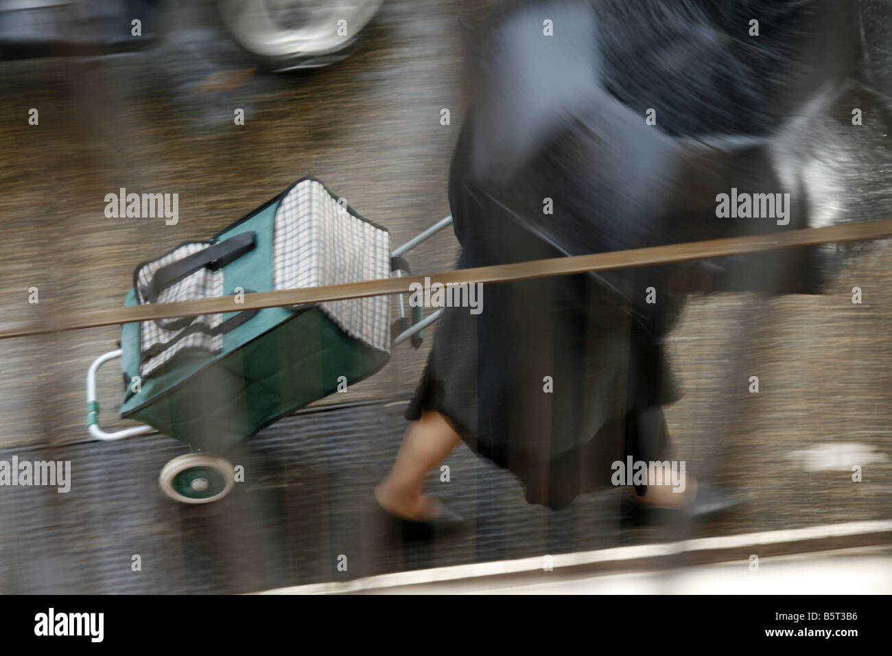 woman with umbrella and shopping trolley in rain in town Stock Photo ...
