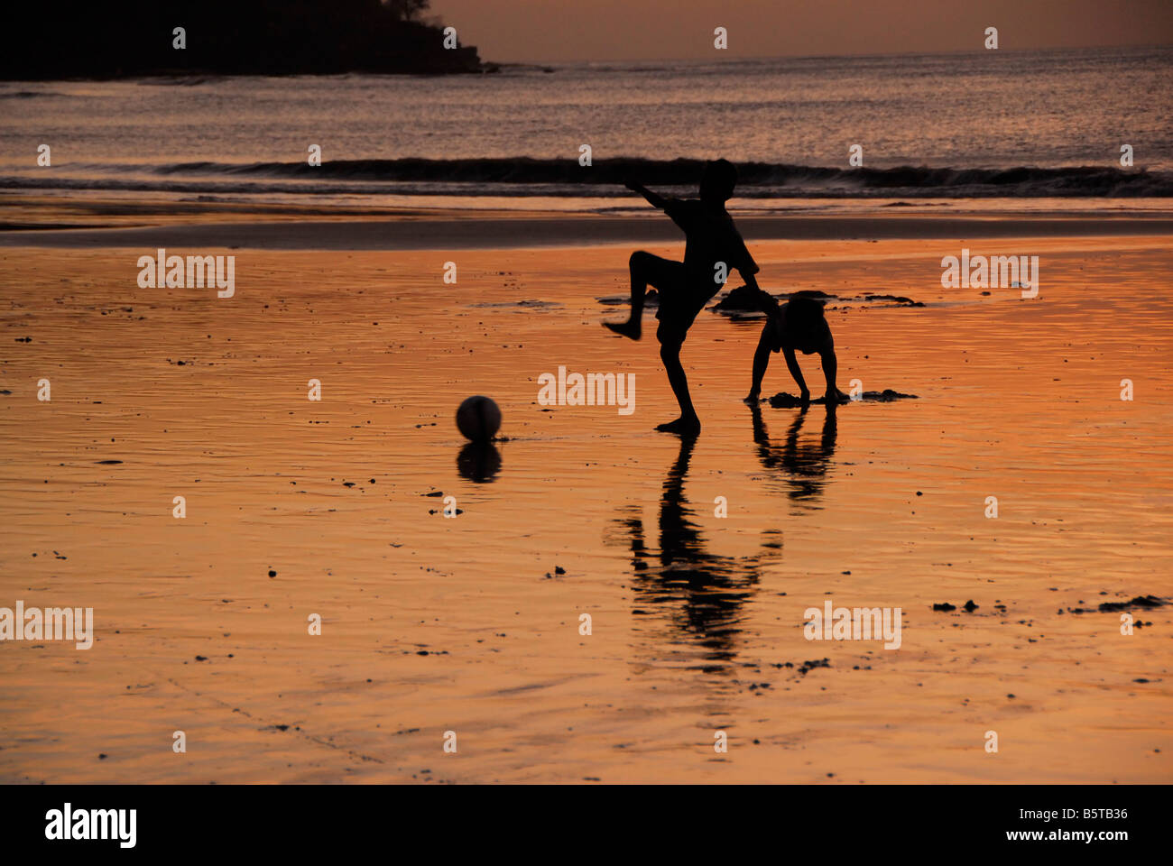 Boy and his dog playing football at sunset, Jimbaran beach,Bali ...