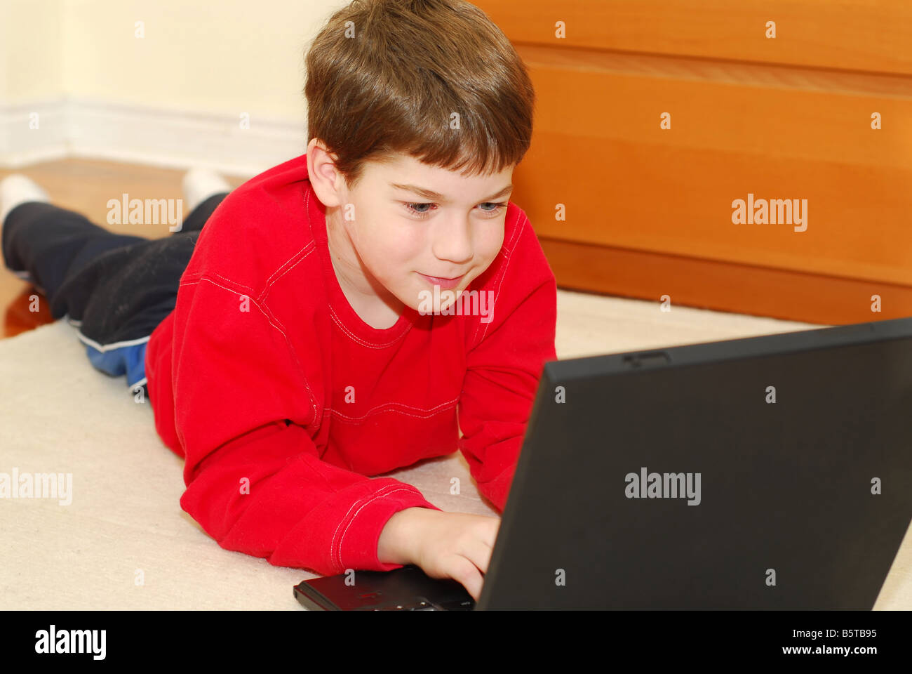 Young boy lying on the floor with portable computer Stock Photo - Alamy