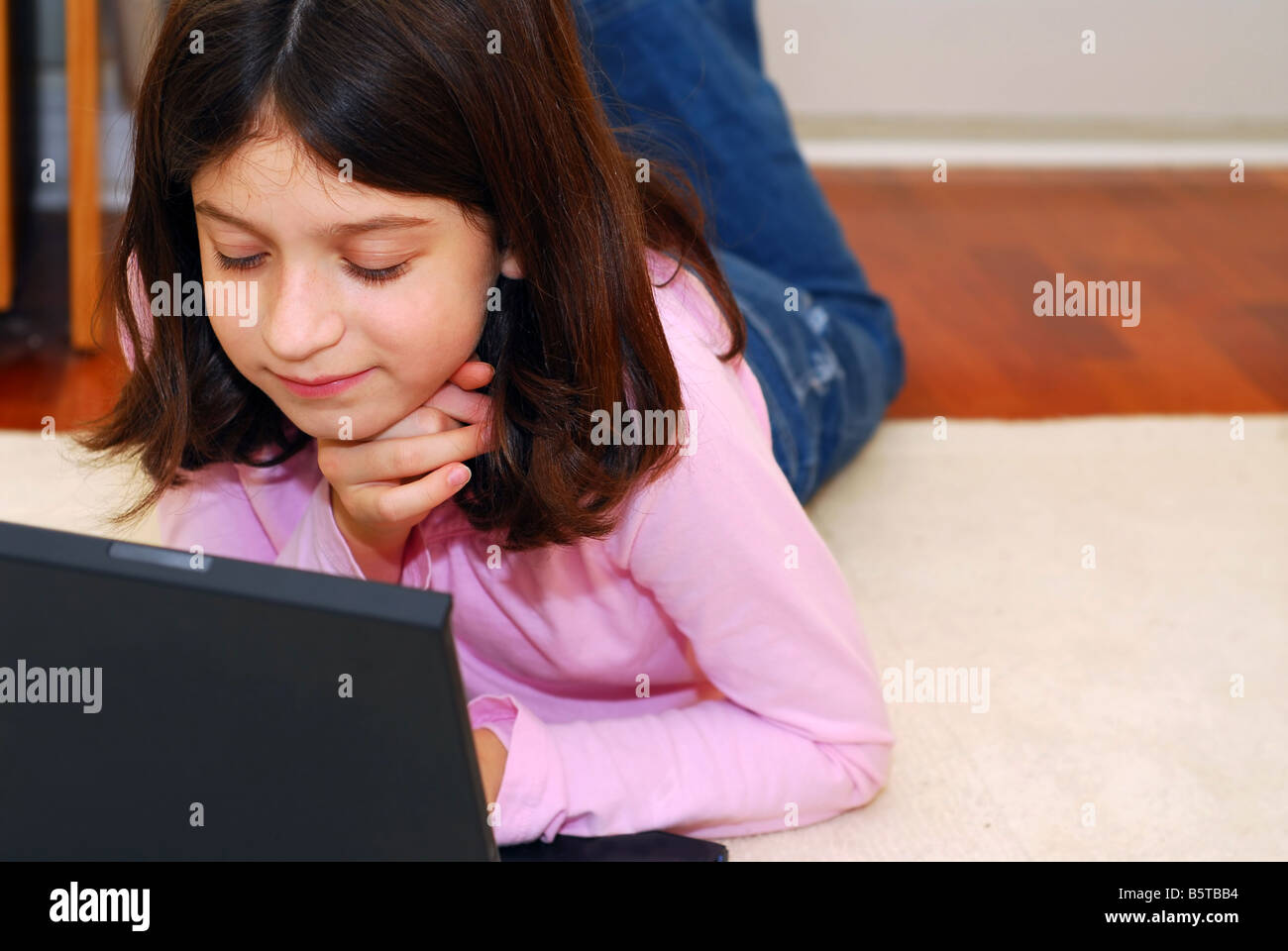 Portrait of a young girl lying on the floor and looking into computer ...