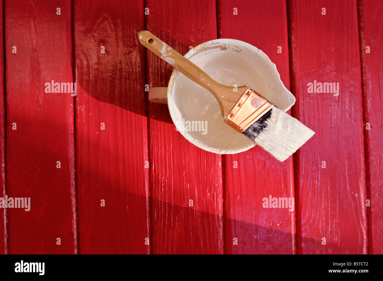 Paint brush, pail and white paint on freshly painted red floor Stock ...