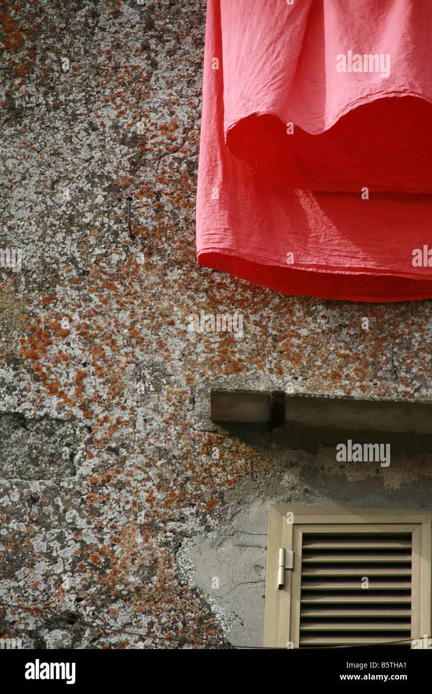 one red bed sheet hanging in street window, italy Stock Photo - Alamy