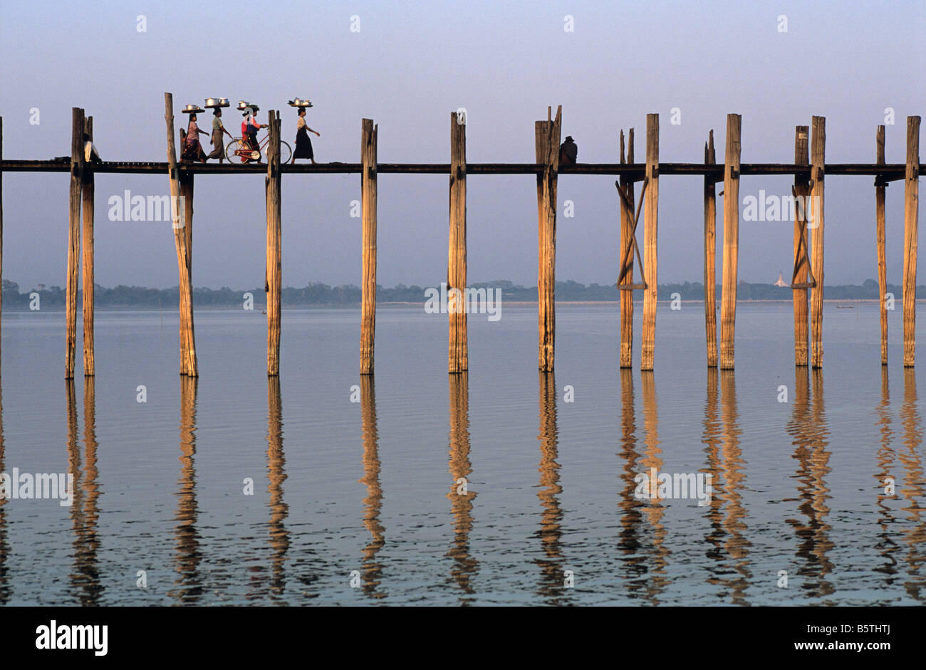 Burmese women cross U Bein's Bridge, the world's longest teak bridge ...