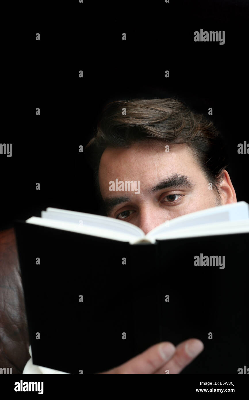 Man concentrated reading a book with black space above Stock Photo - Alamy