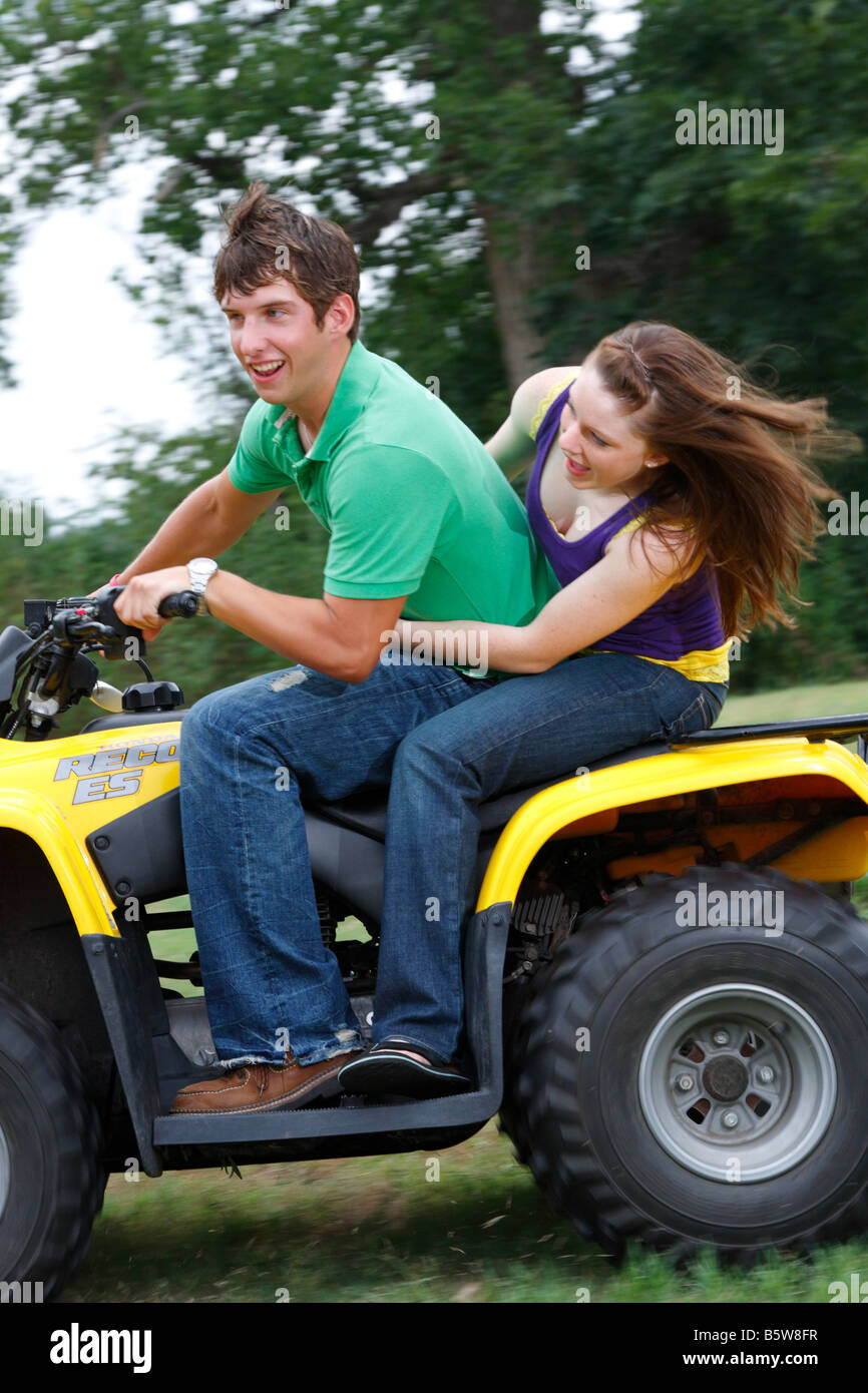 Two teens having fun riding a four wheeler Stock Photo - Alamy