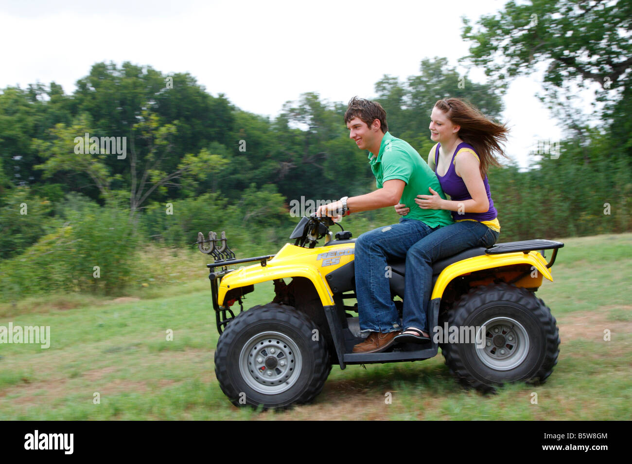 Two teens having fun riding a four wheeler Stock Photo - Alamy