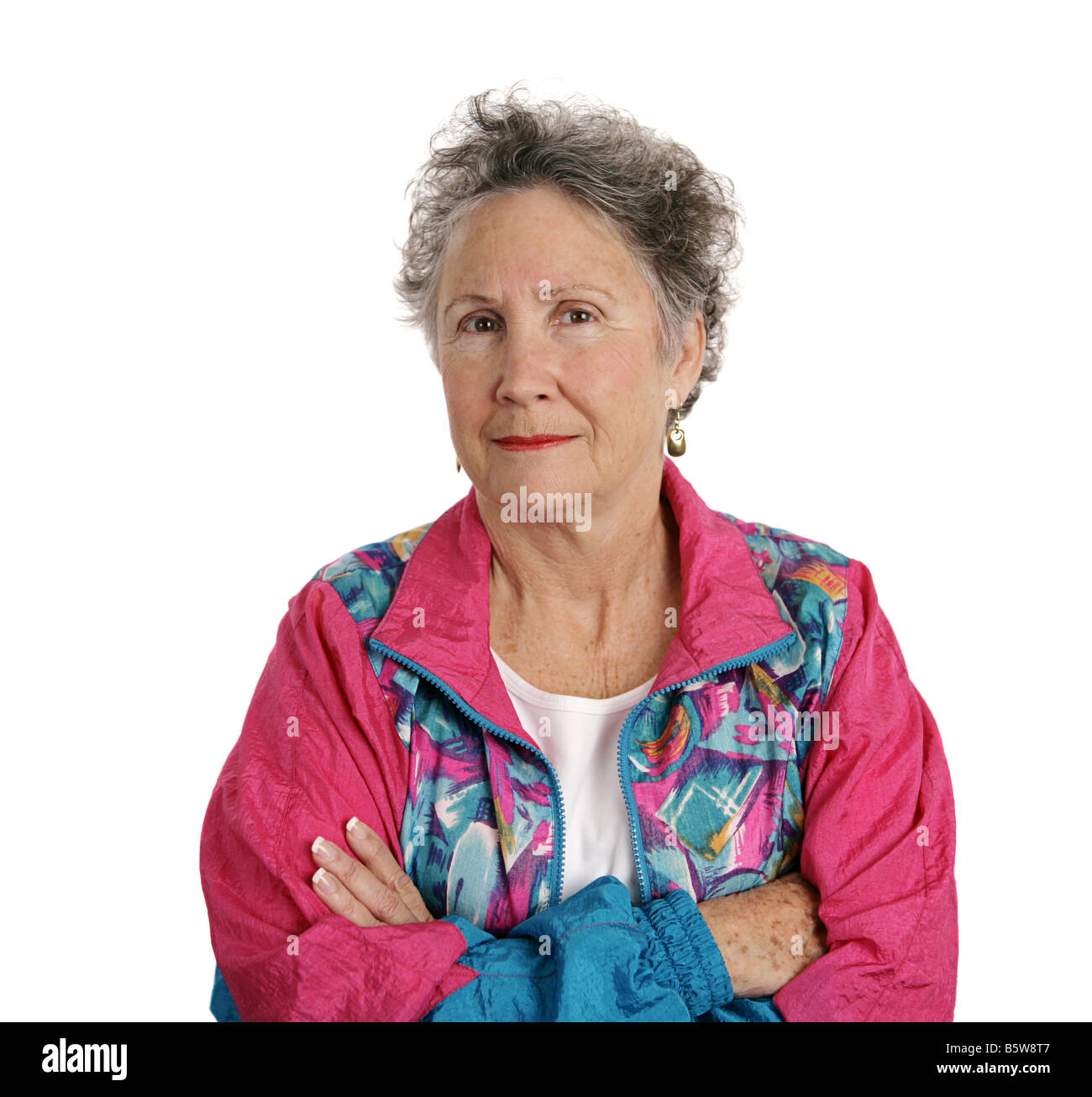 A senior woman in a track suit with her arms crossed and a distrustful ...