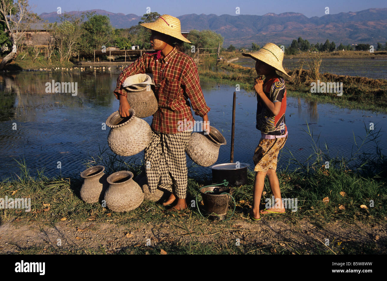 Burmese Intha woman and son carrying pots, Lake Inle, Burma or Myanmar ...