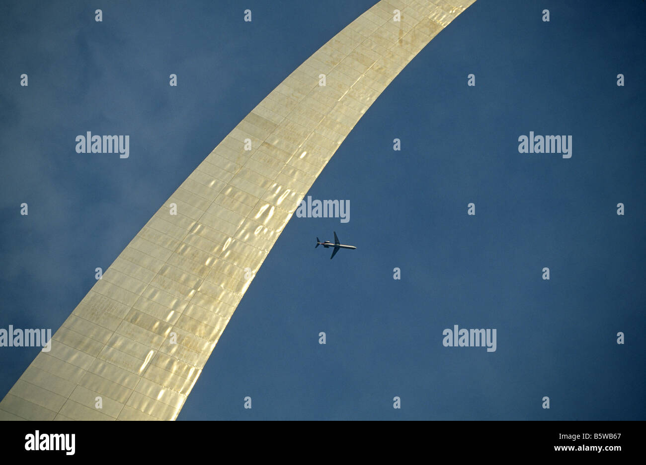 A passenger commercial jet plane flies over the St Louis Arch along the ...