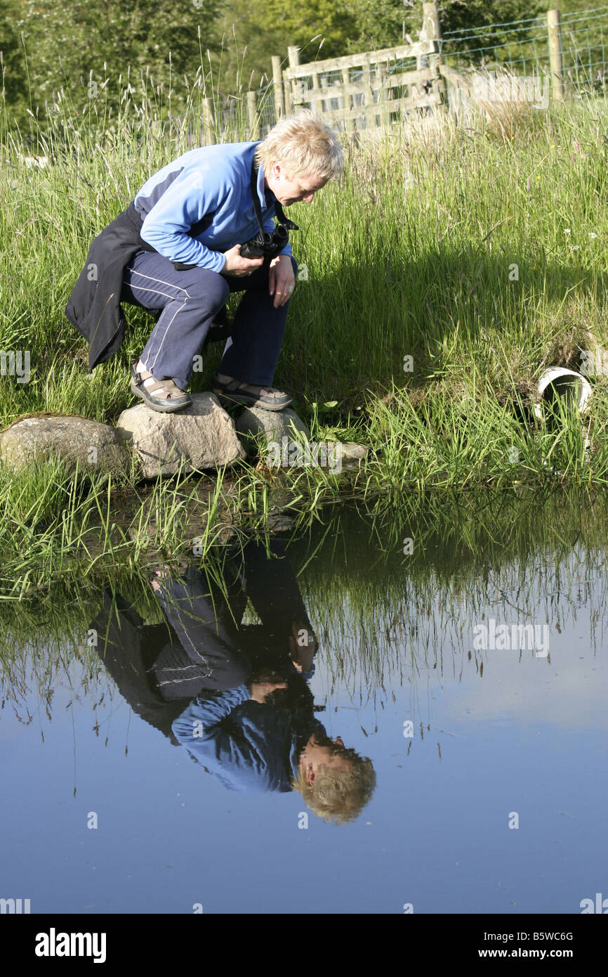 A woman looking into a pond at her reflection Stock Photo - Alamy