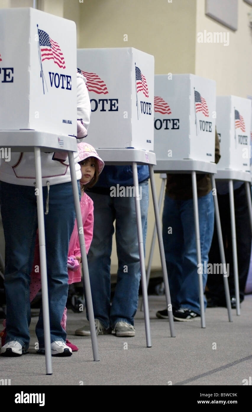 Girl stands behind her Mother as she marks her ballot in San Jose, CA ...