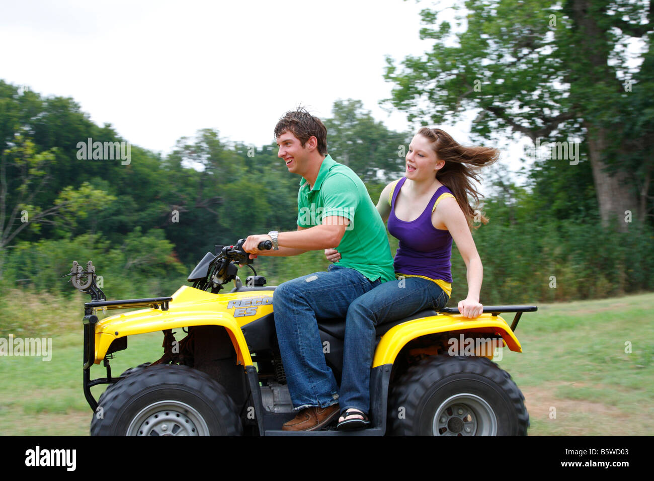 Two teens having fun riding a four wheeler Stock Photo - Alamy