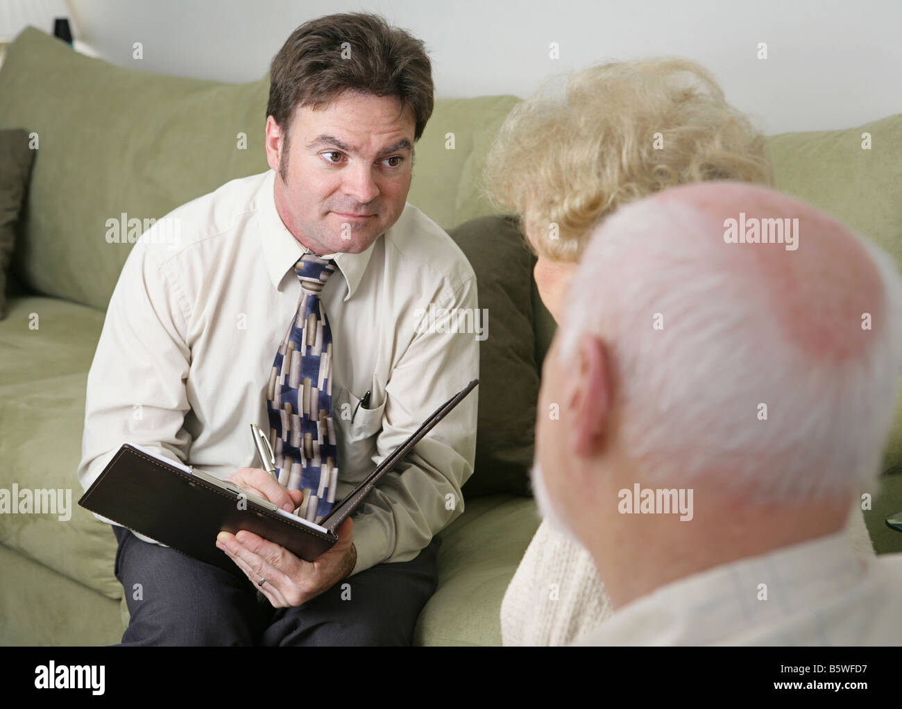 A counselor with a caring expression sitting across from an elderly ...