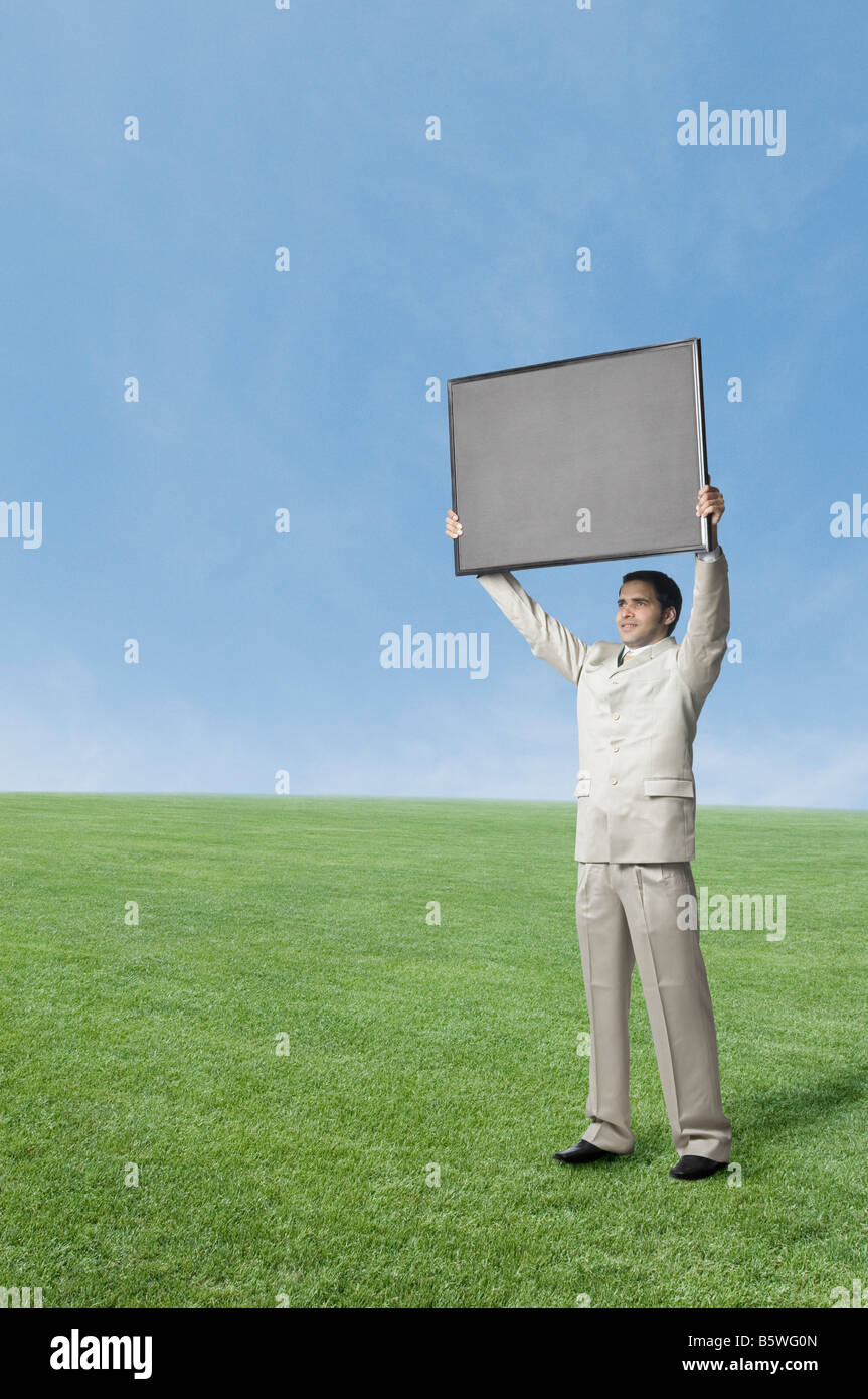 Businessman standing in a lawn and holding a sign Stock Photo - Alamy
