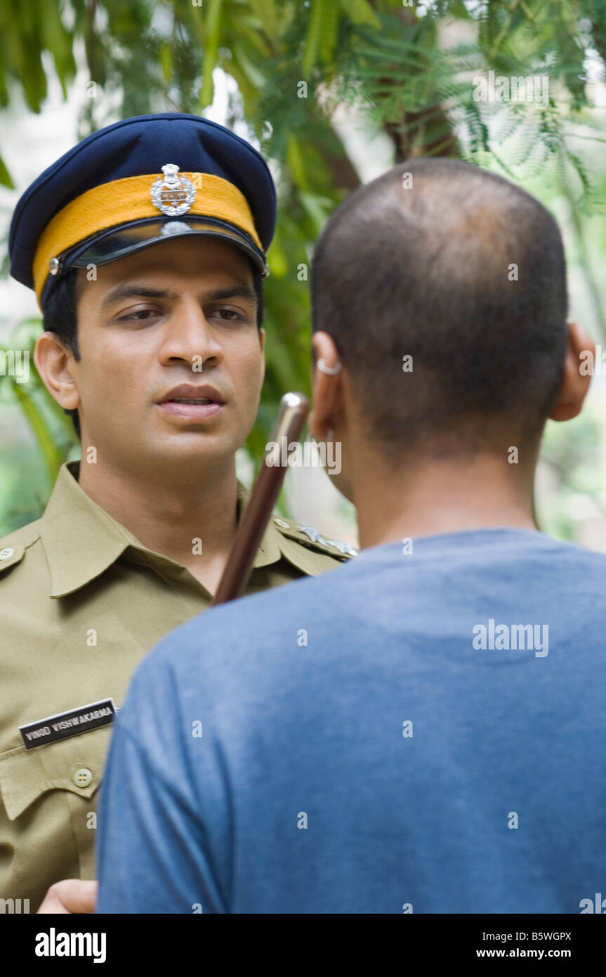 Close-up of a policeman showing a nightstick to a young man Stock Photo ...