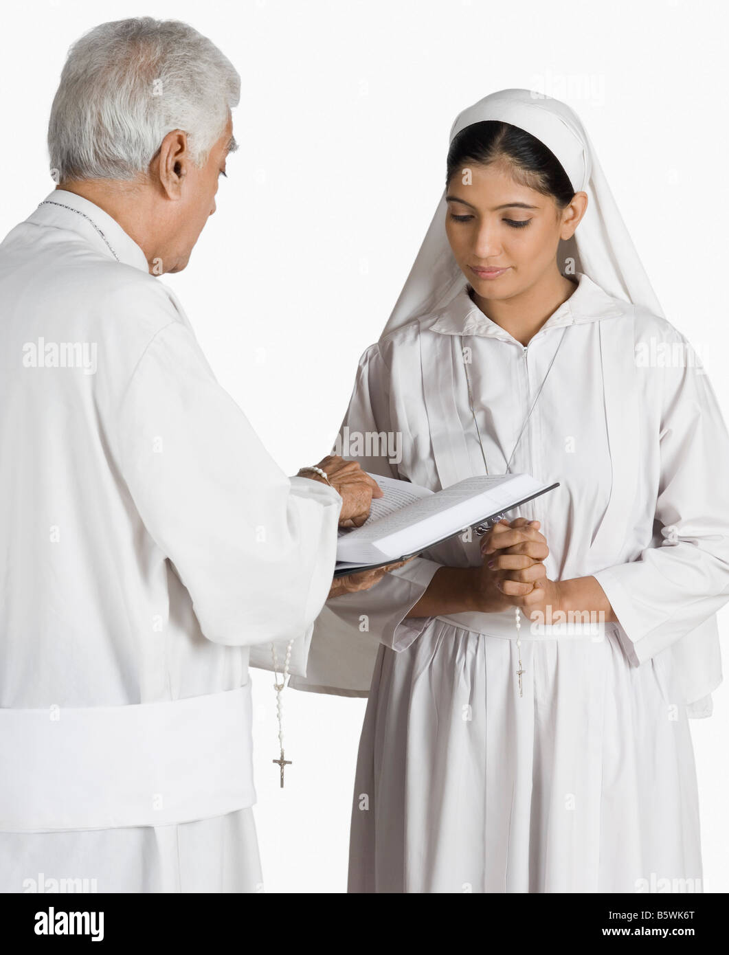 Priest and a nun looking at the Bible Stock Photo - Alamy