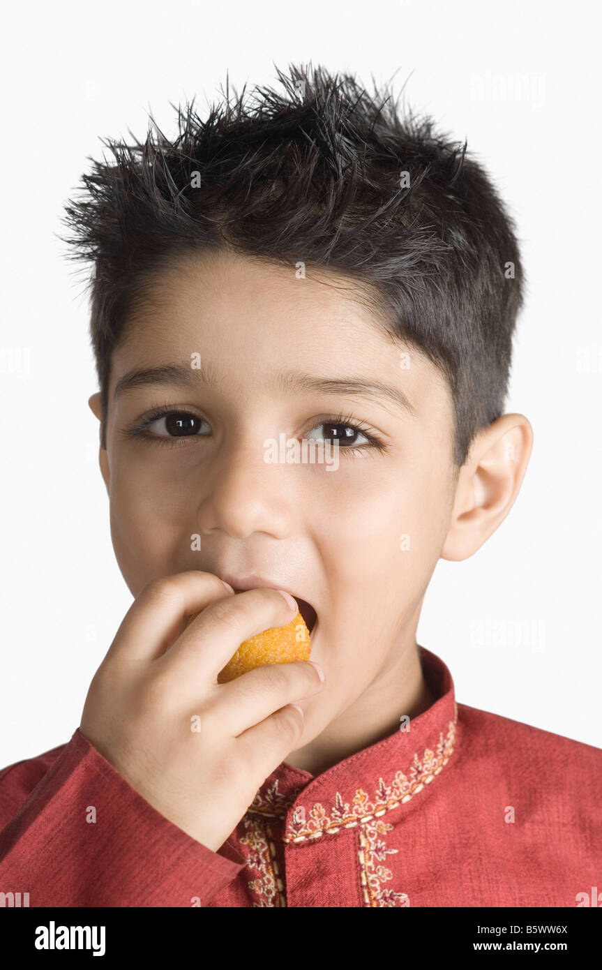Portrait of a boy eating laddu Stock Photo - Alamy
