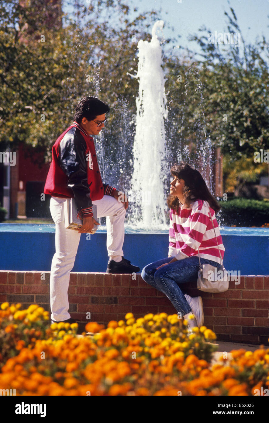 Hispanic couple talk in front of fountain on college campus Stock Photo ...
